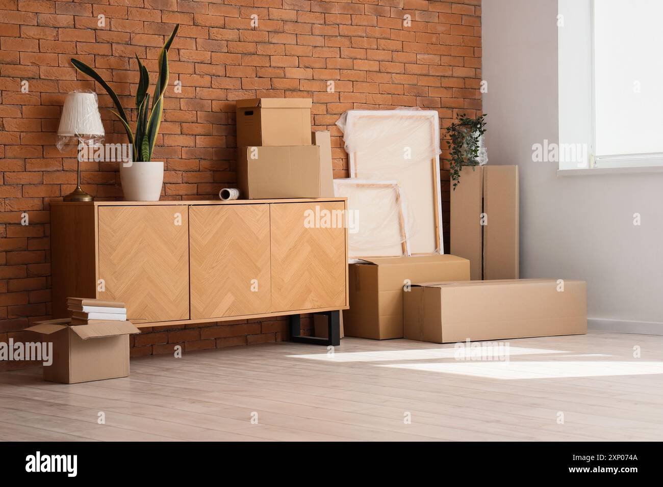 Furniture, houseplant and cardboard boxes with belongings near brown ...