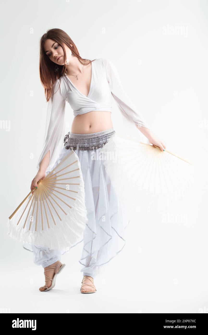 Young woman dances gracefully with fans in a studio, showcasing her ... Young woman dances gracefully with fans in a studio, showcasing her ...