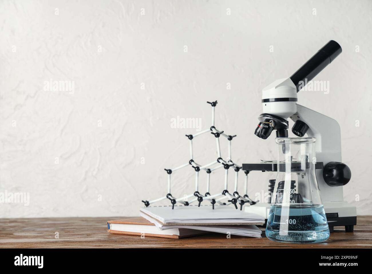 Modern microscope with chemical flask, molecular model and notebooks on ...