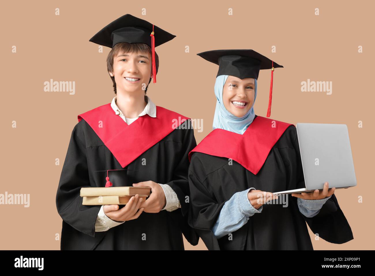 Graduating students with laptop and books on beige background Stock ...