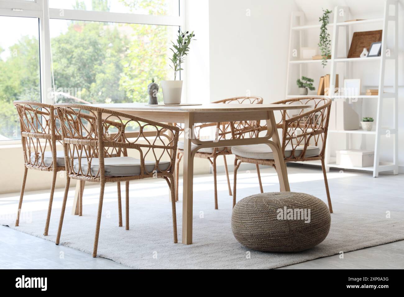 Interior of dining room with table, shelf unit and pouf Stock Photo - Alamy
