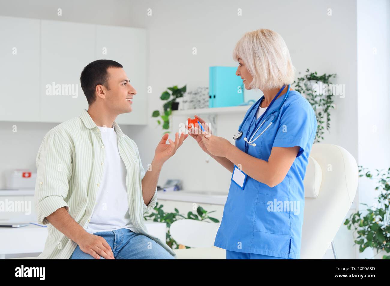 Female endocrinologist showing thyroid gland model to male patient in ...