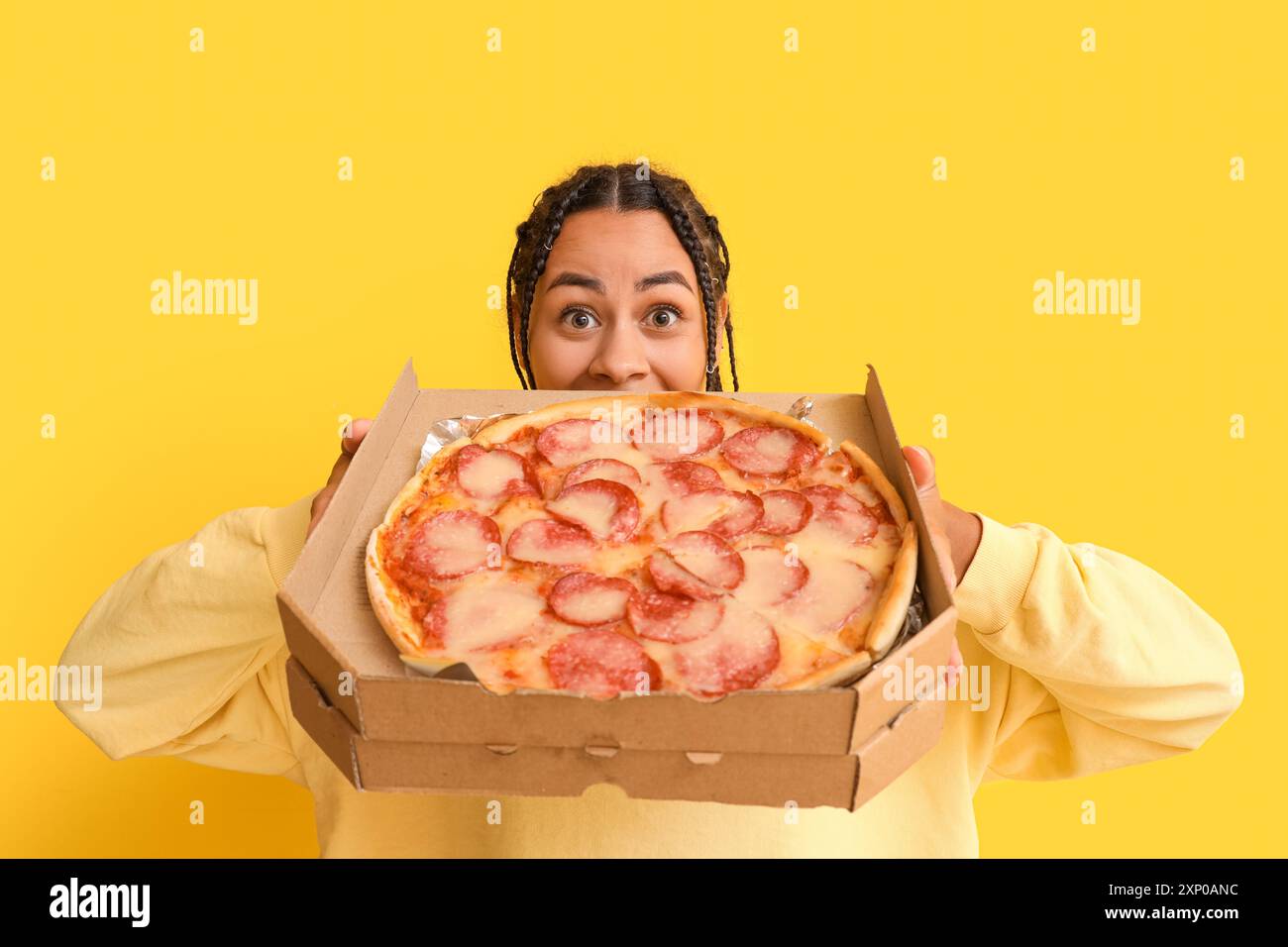 Happy African-American woman with tasty pepperoni pizza on yellow ...