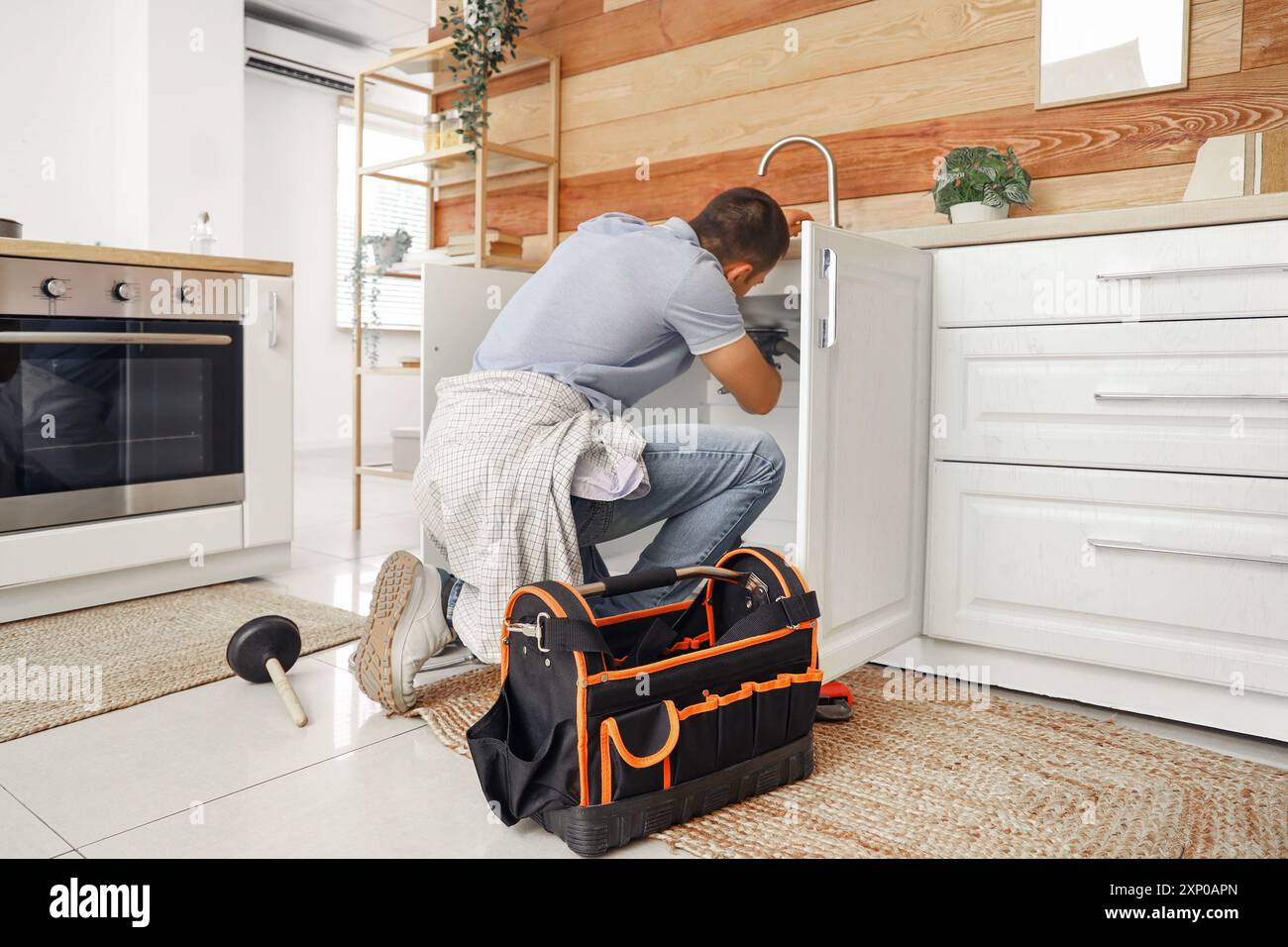 Male plumber fixing sink in kitchen, back view Stock Photo - Alamy