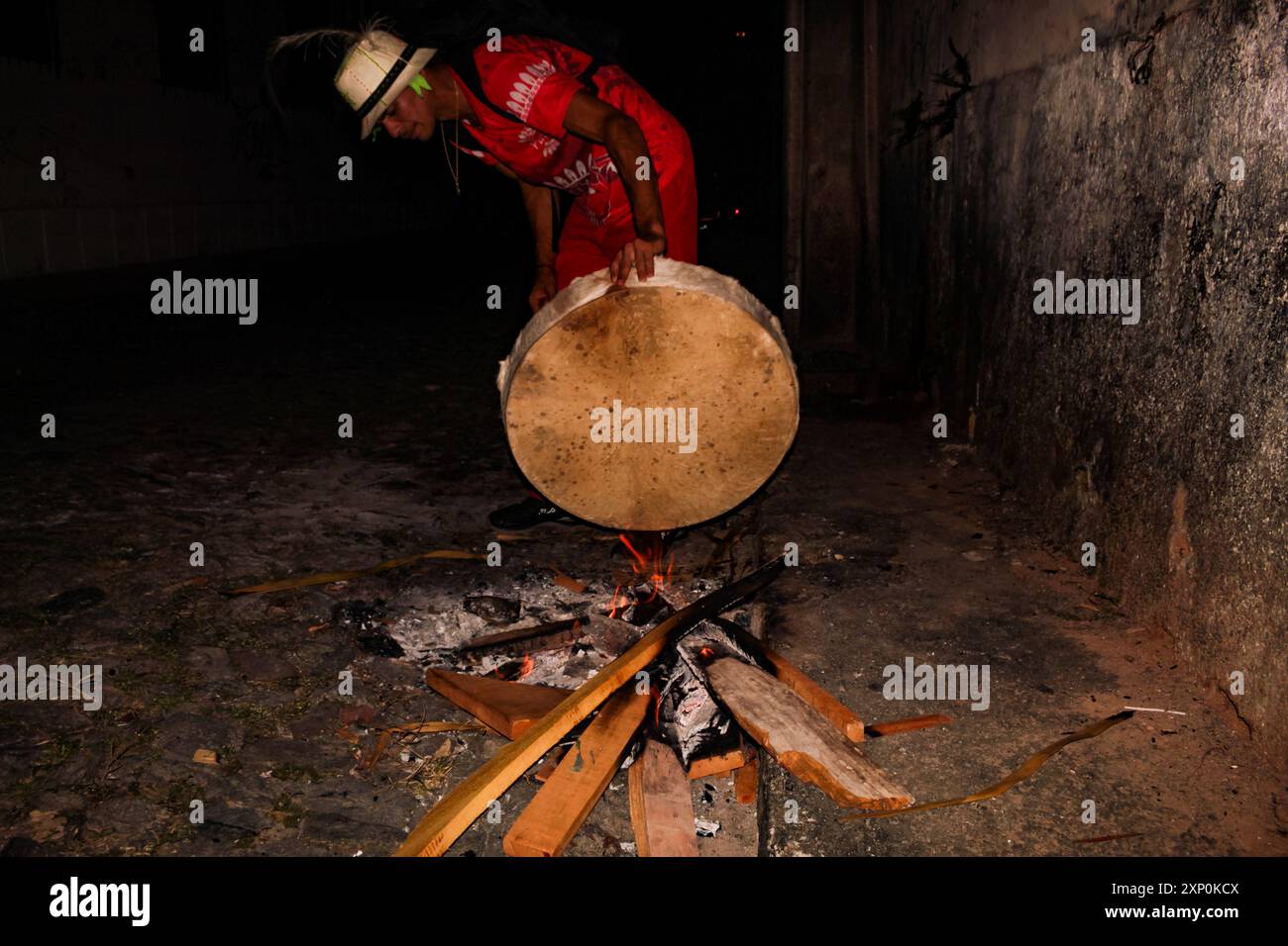 Percussionist tuning a large tambourine on a bonfire to play the ...
