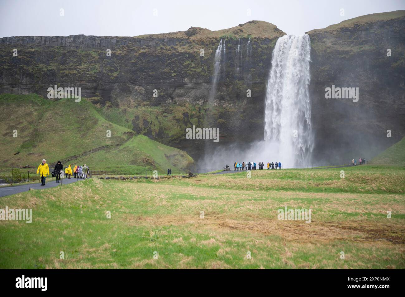 Seljalandsfoss Waterfall with walking path and tourist in rain voer in ...