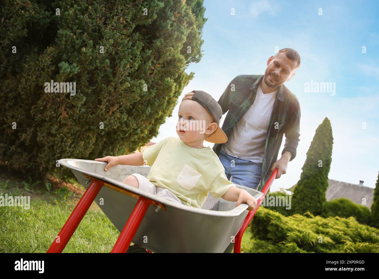 Father pushing wheelbarrow with his son outdoors, selective focus Stock ...