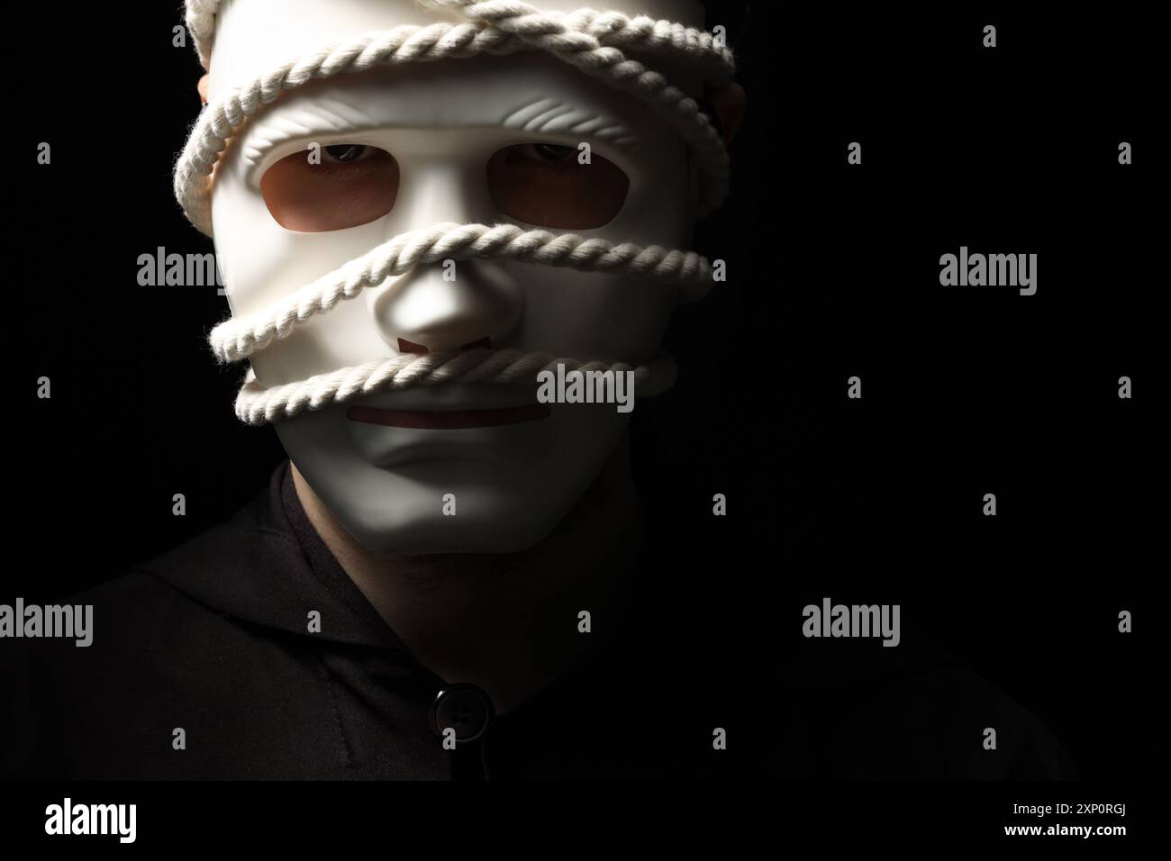 Theatrical performance. Man with plastic mask and hemp rope on black ...