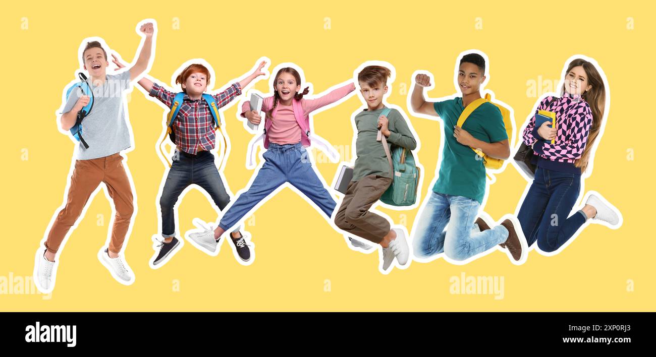 Cheerful school children jumping together on yellow background Stock ...