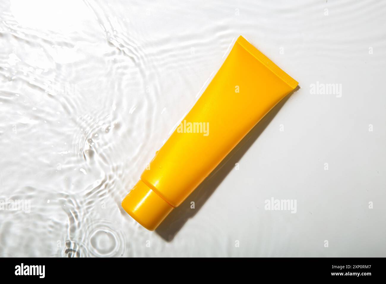 Cosmetic product. Tube with cream in water on light background, top ...