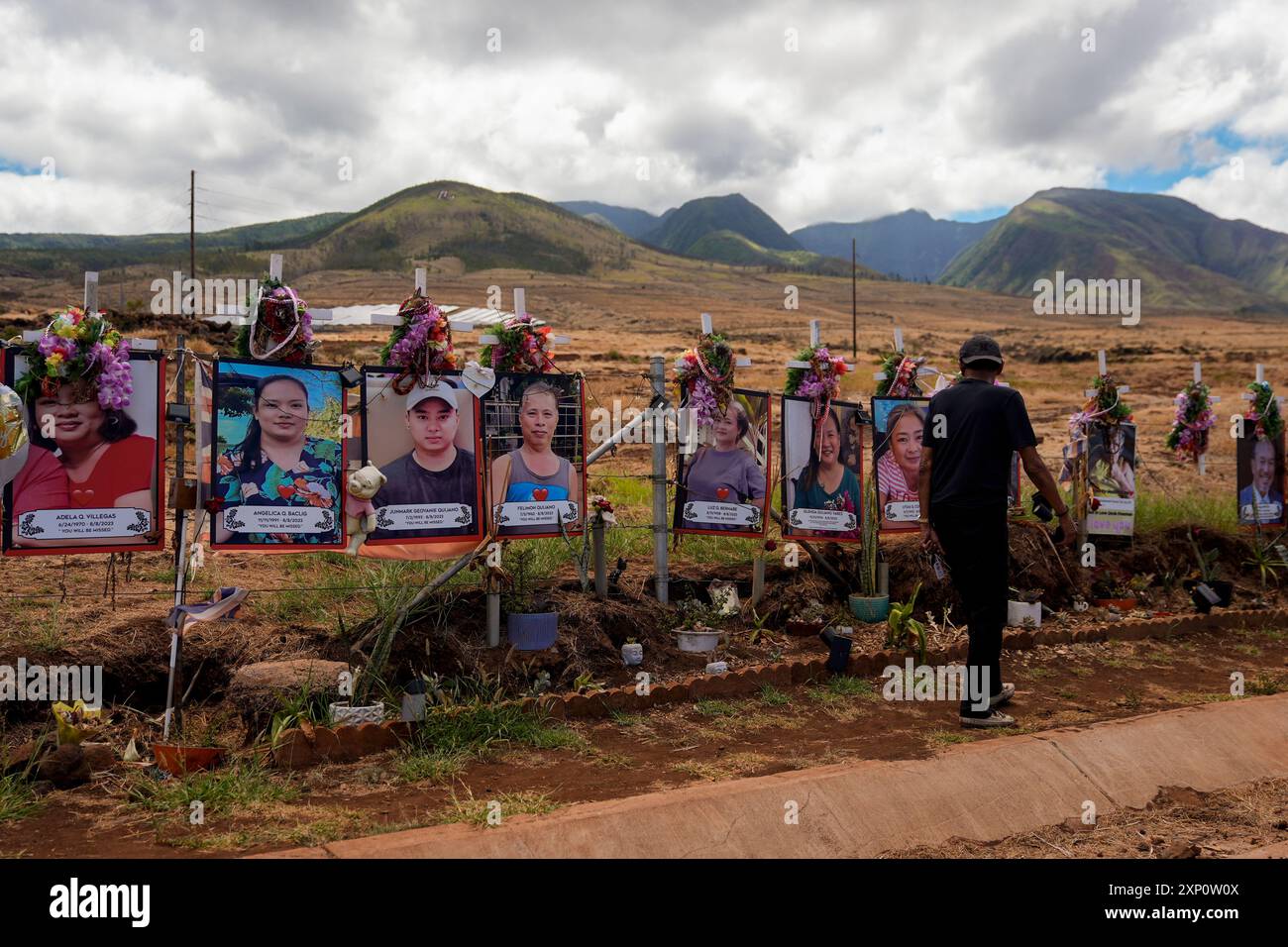 A visitor walks by photos of victims of the August 2023 wildfire at a ...