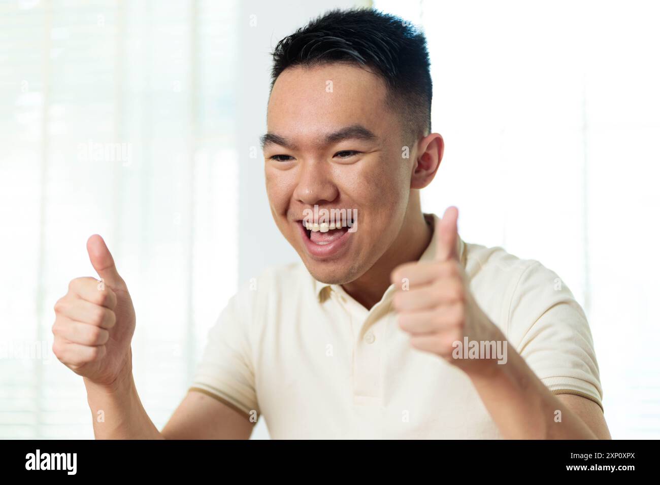 A cheerful teen boy dressed in a white shirt is enthusiastically giving ...
