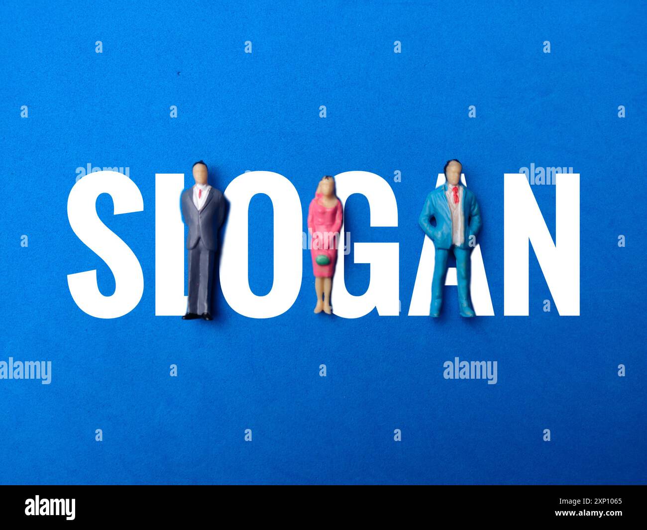 Word SLOGAN with miniature people on blue background Stock Photo - Alamy
