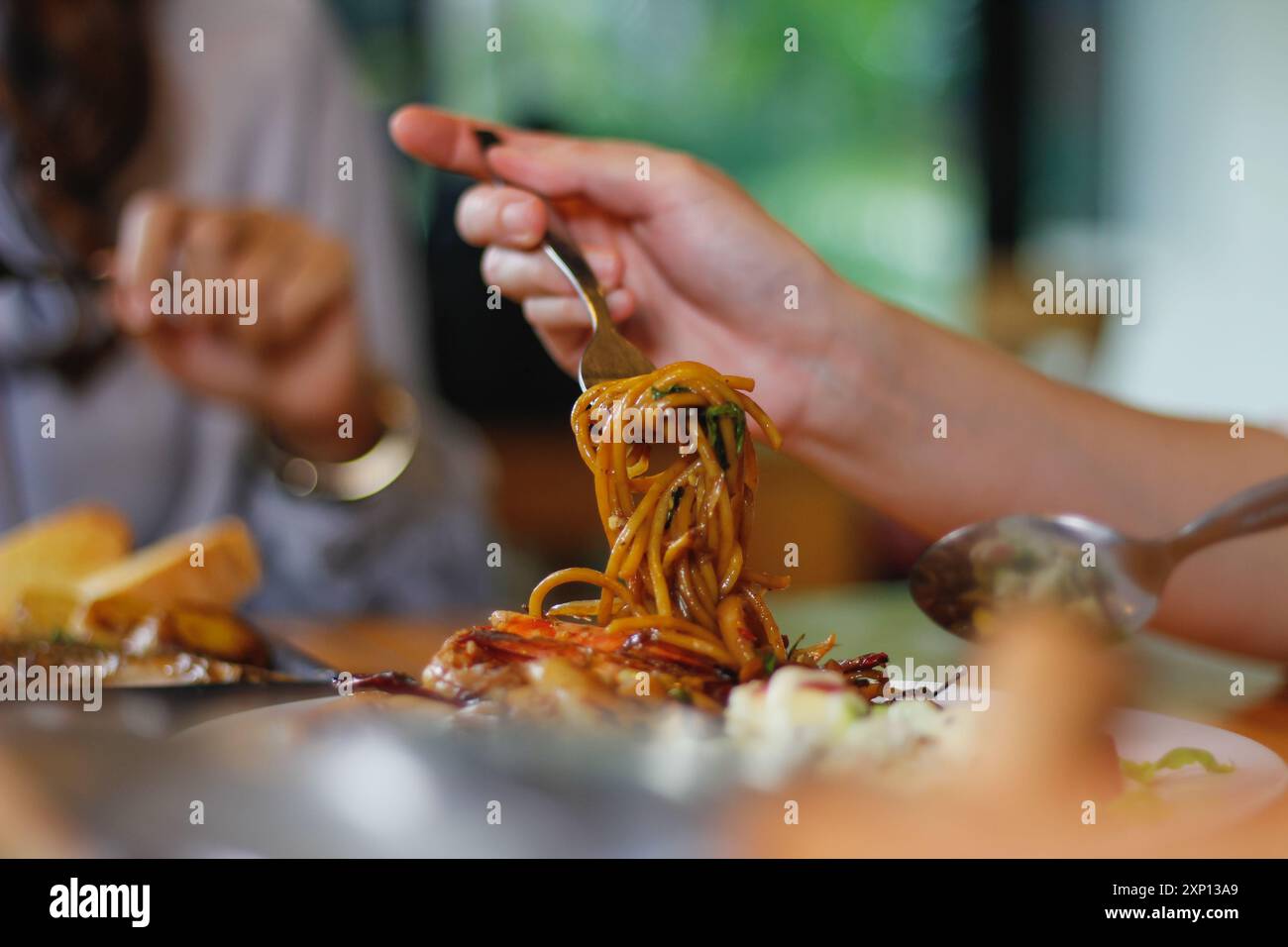 Asian woman eating spaghetti with spicy seafood sauce in a restaurant ...