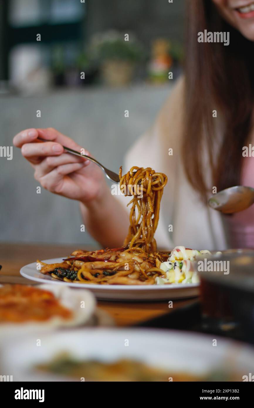 Asian woman eating spaghetti with spicy seafood sauce in a restaurant ...
