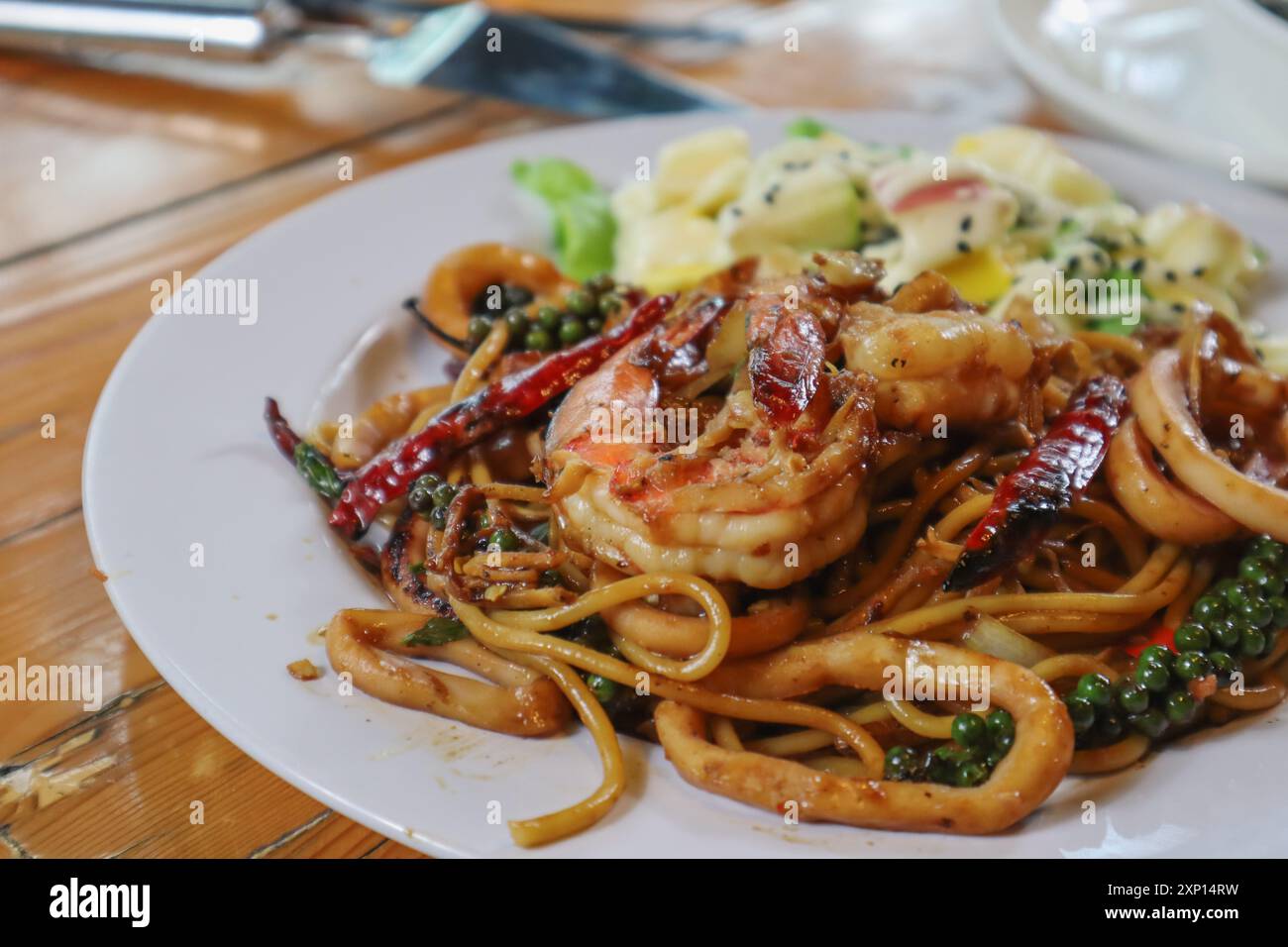 Asian woman eating spaghetti with spicy seafood sauce in a restaurant ...