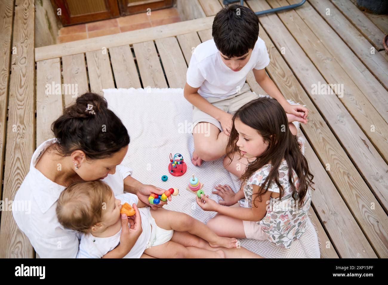 Mother and three children enjoying playtime with toys outdoors on a ...