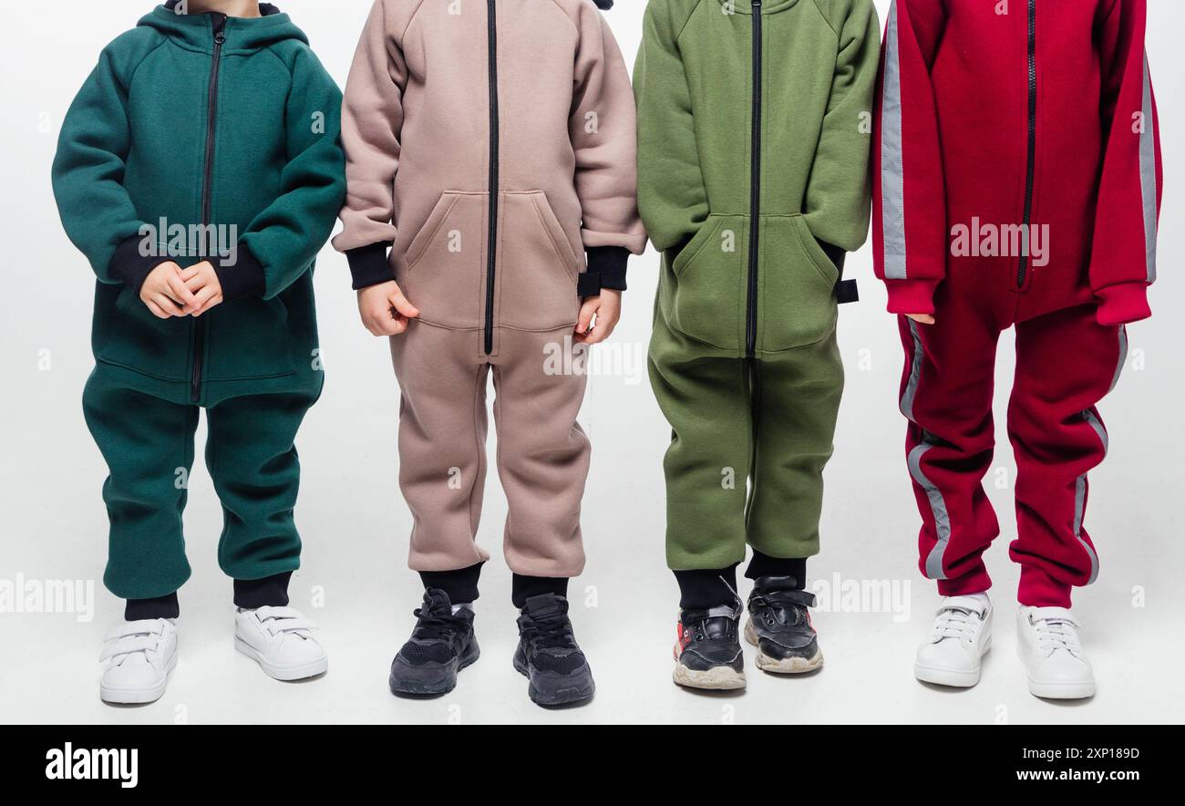 Four children stand in a row wearing green, brown, olive, and red ...