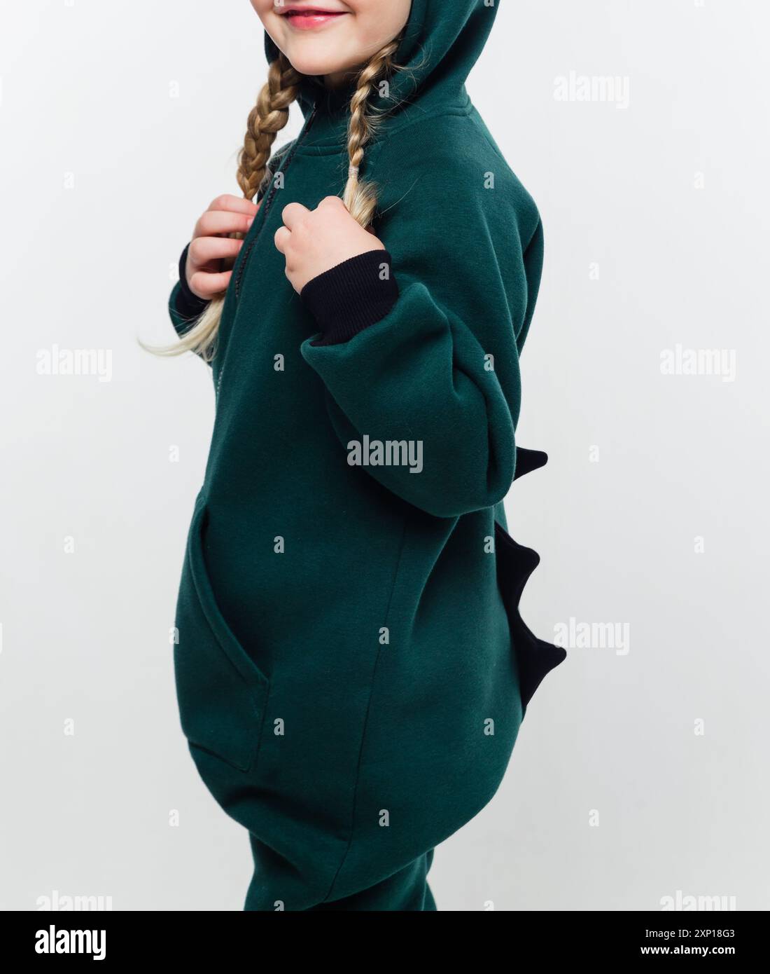 A young girl wearing a green hoodie with black dinosaur spikes on the ...