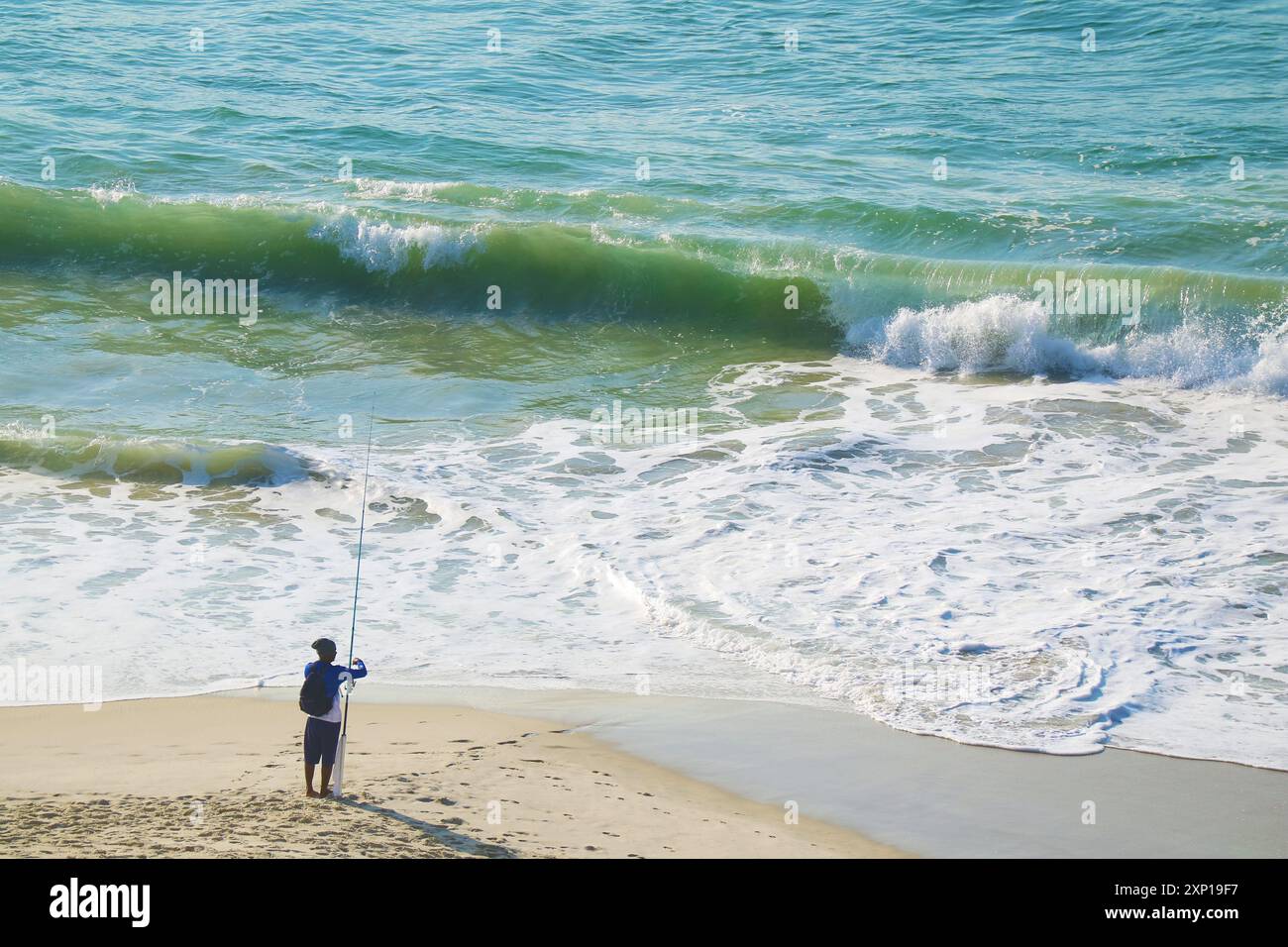 People with a fishing rod on the waves crashed beach Stock Photo - Alamy