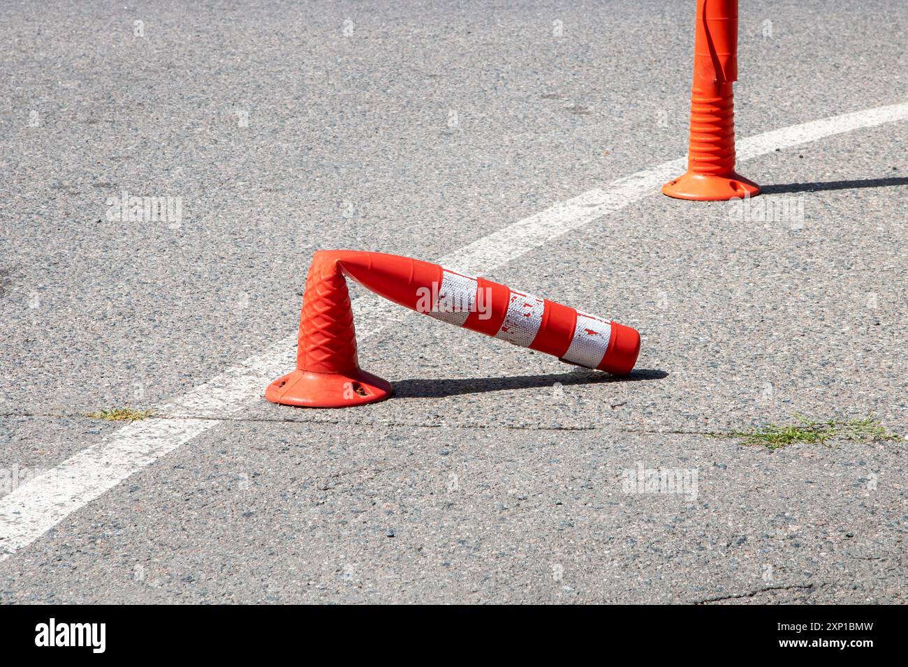 A bright red and white traffic cone is currently laying on the side of ...