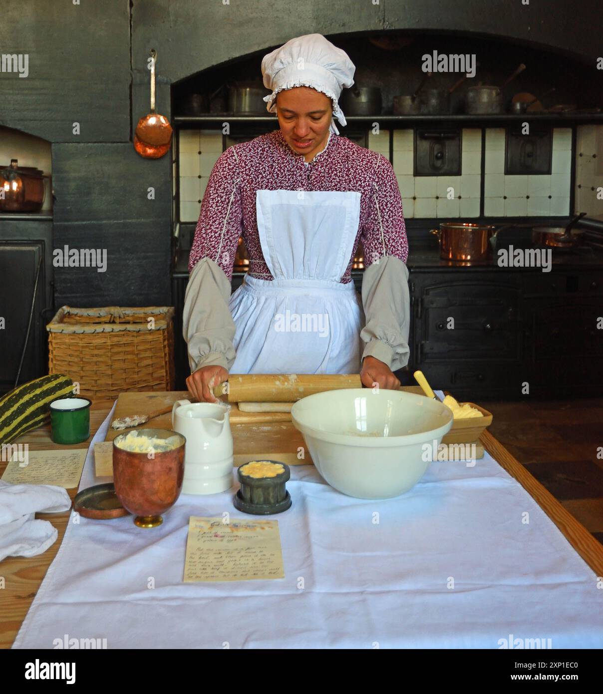 Victorian Kitchen maid making pastry in old kitchen using rolling pin ...