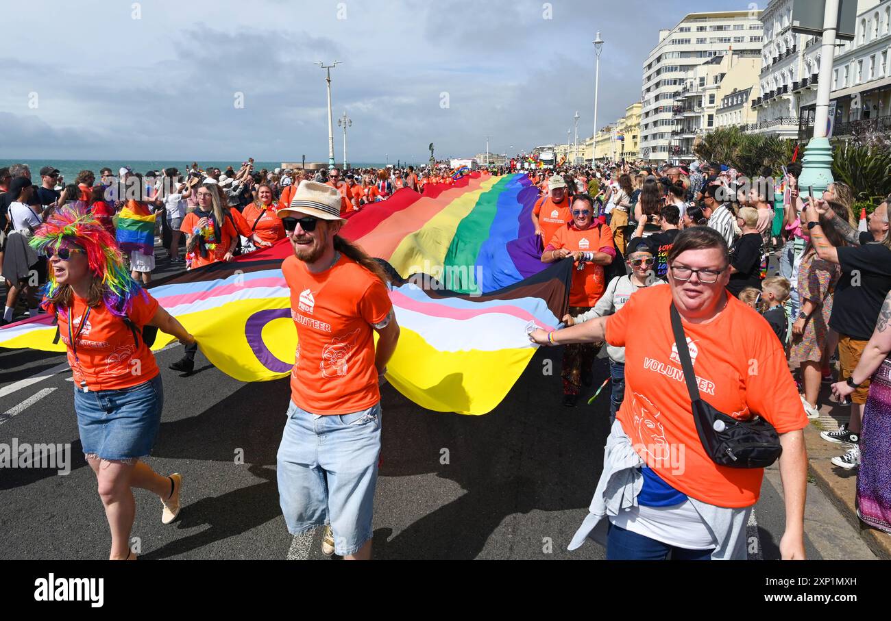 Brighton UK 3rd August 2024 - A giant rainbow flag is carries though ...