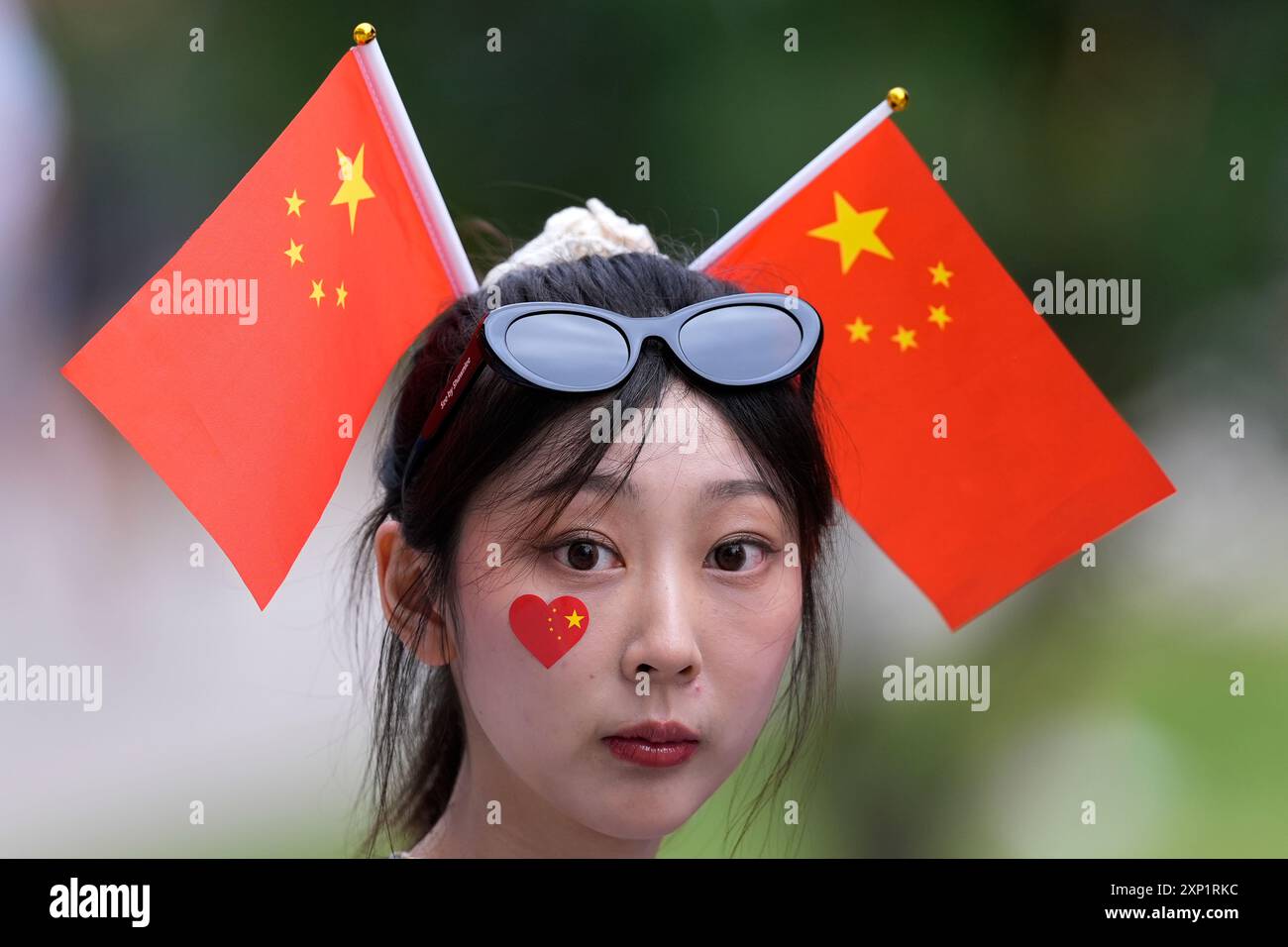 A Chinese spectator places China's national flags on her hair and face ...