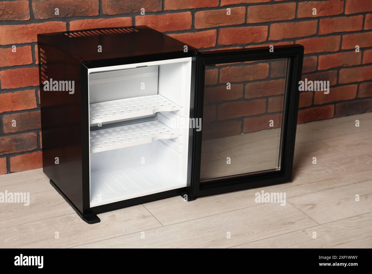 Empty mini refrigerator near brick wall indoors Stock Photo - Alamy