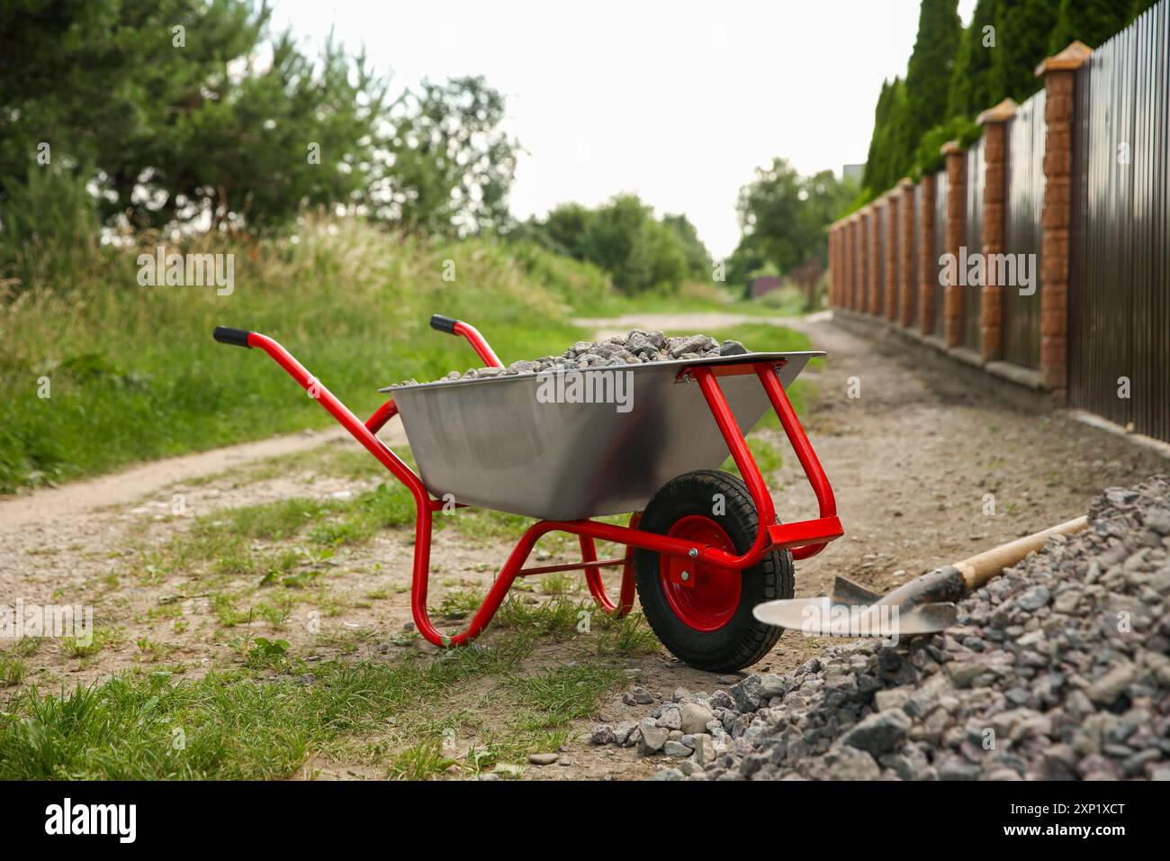 Wheelbarrow full of stones and shovel outdoors Stock Photo - Alamy