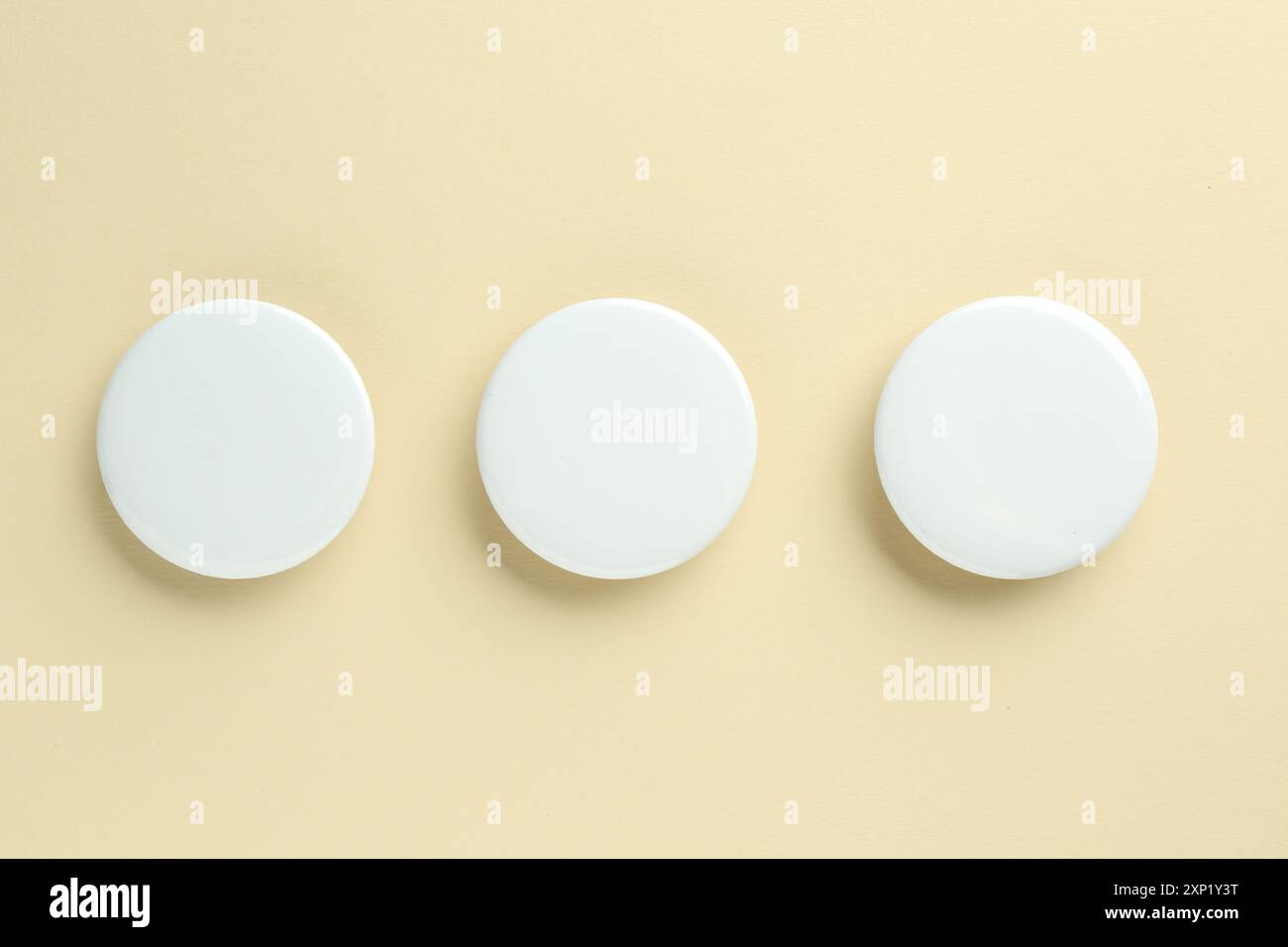 White button badges on beige background, flat lay. Mockup for design ...