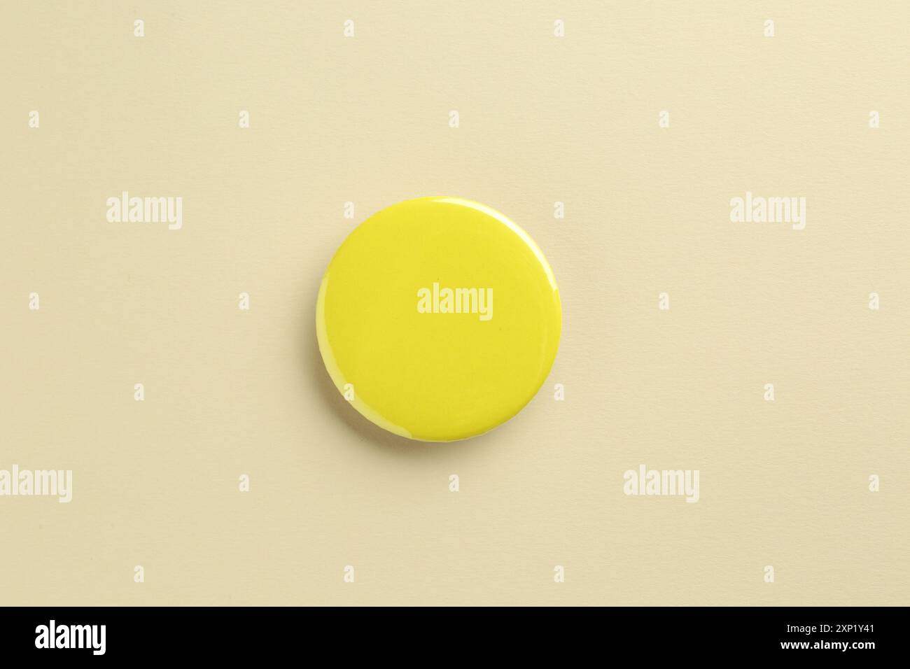 Yellow button badge on beige background, top view. Mockup for design ...