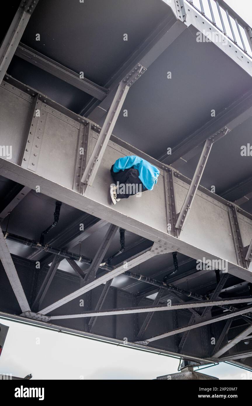 A sculpture of a person hiding under a bridge with a blue jacket in ...