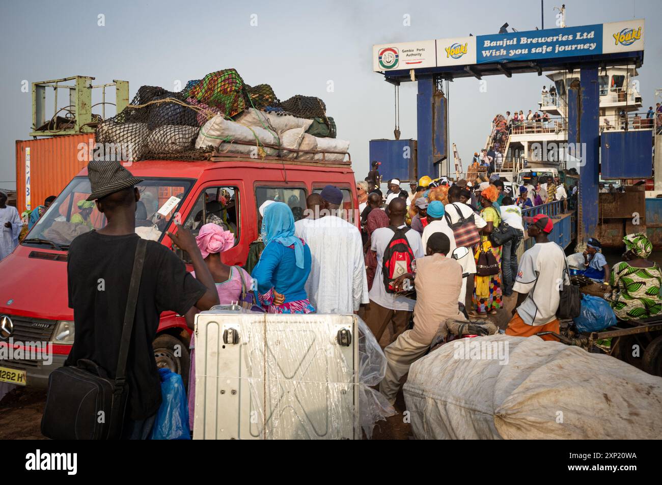 People and vehicles boarding a ferry from Banjul to Barra, Gambia. Busy ...