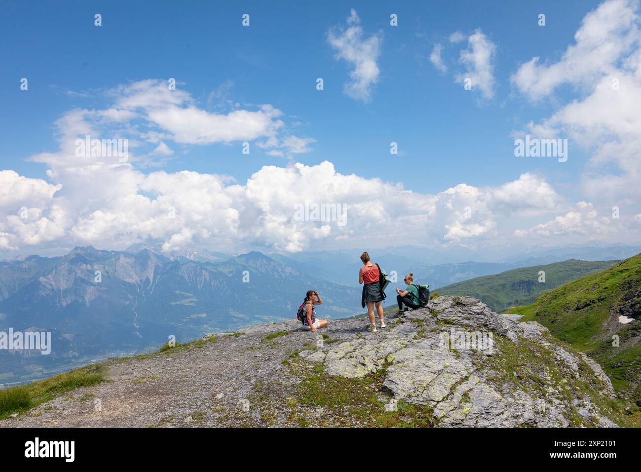 Hikers taking a break at a mountain top of the 5 lakes Hike, at Pizol ...
