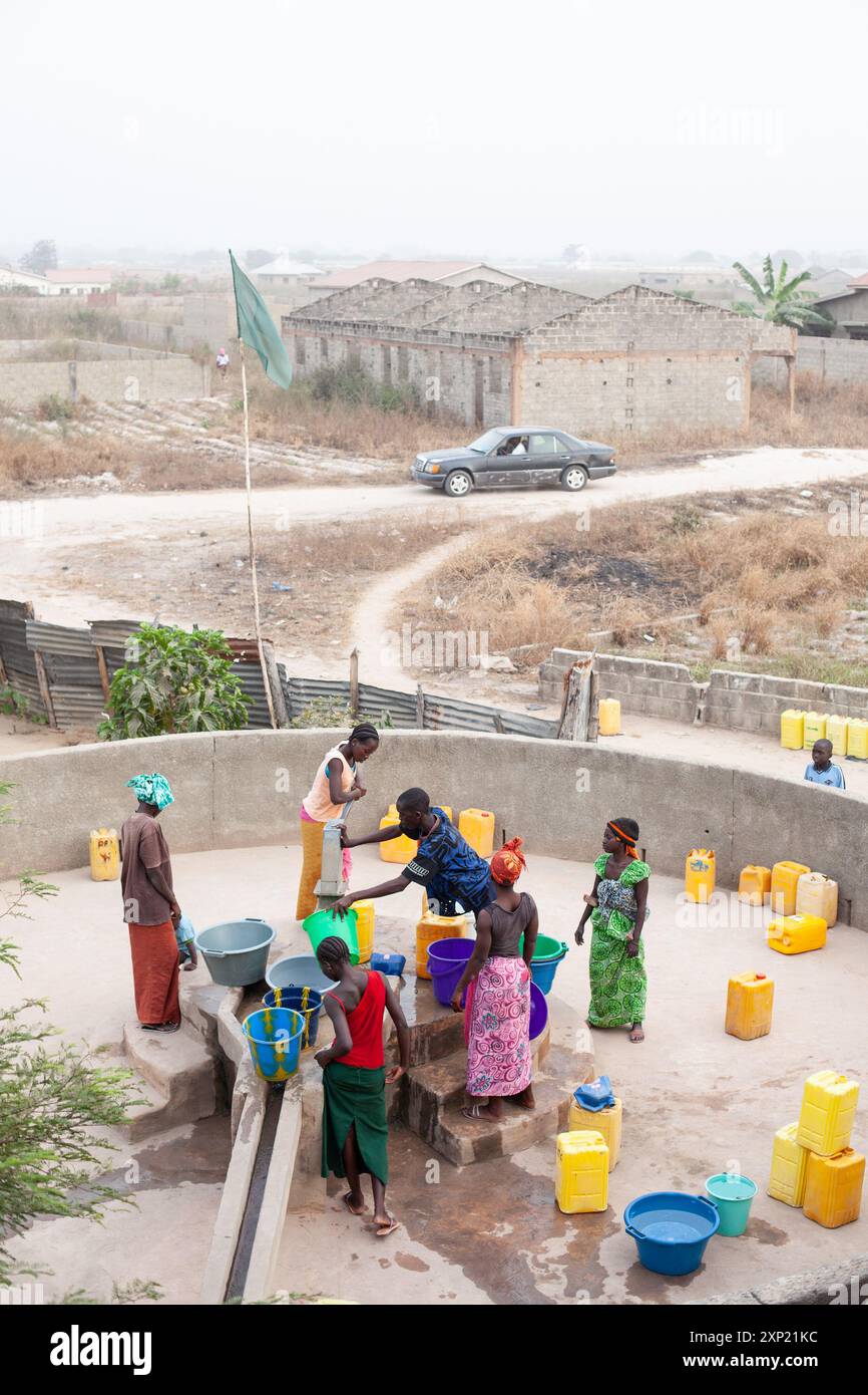 A group of people collecting water from a well in Gambia, representing ...