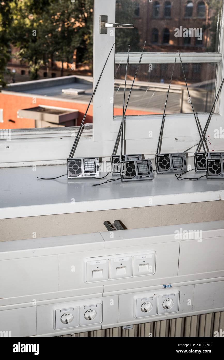 Several retro radios lined up on a windowsill with a view of a red ...