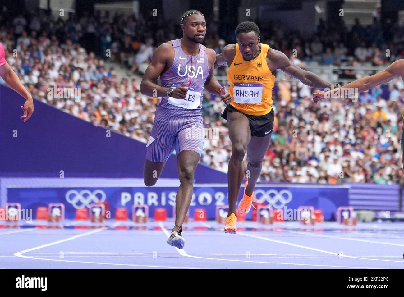 Noah Lyles, left of Team USA crosses the finish line next to Owen Ansah ...