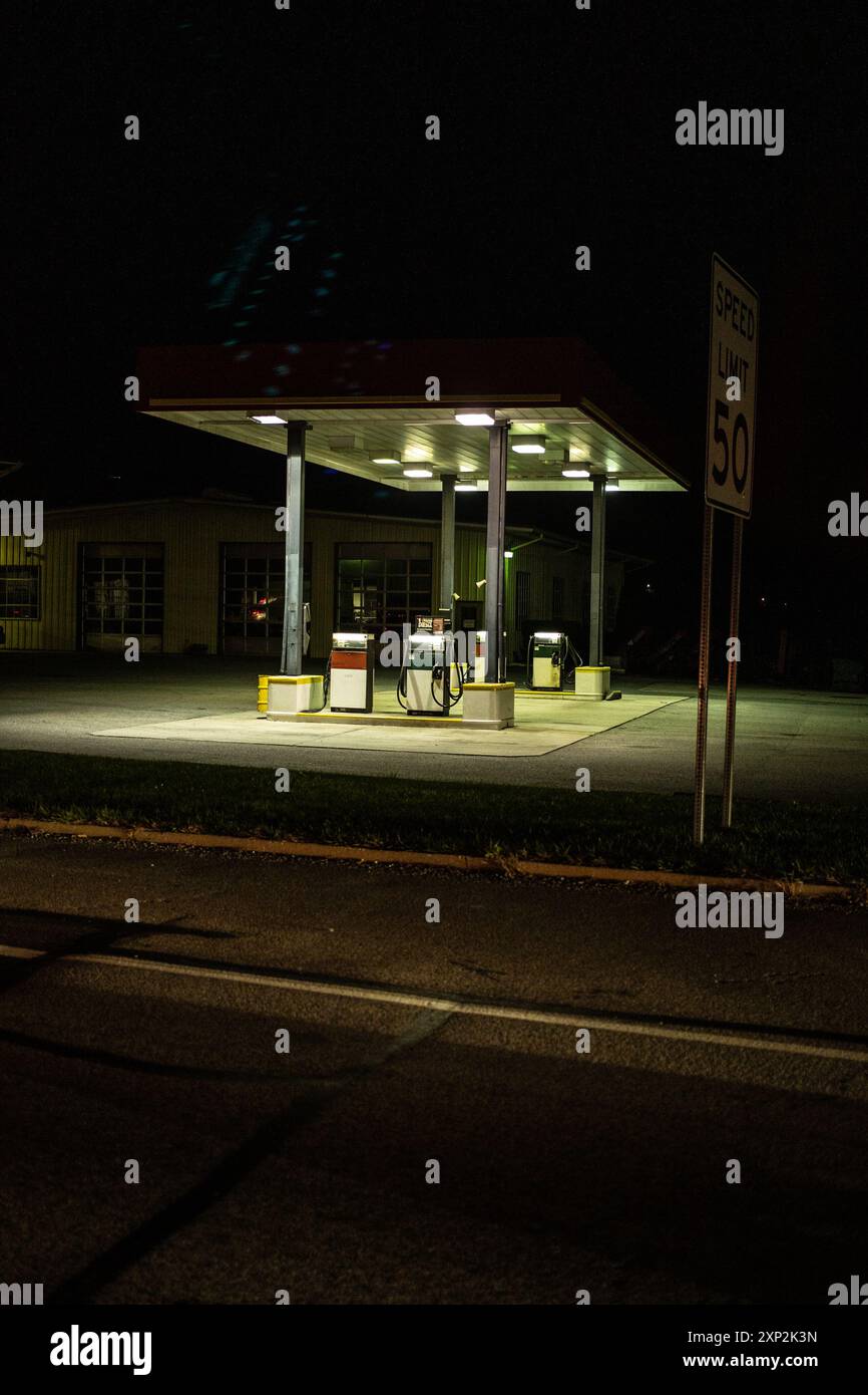 An empty gas station illuminated by artificial lights at night ...