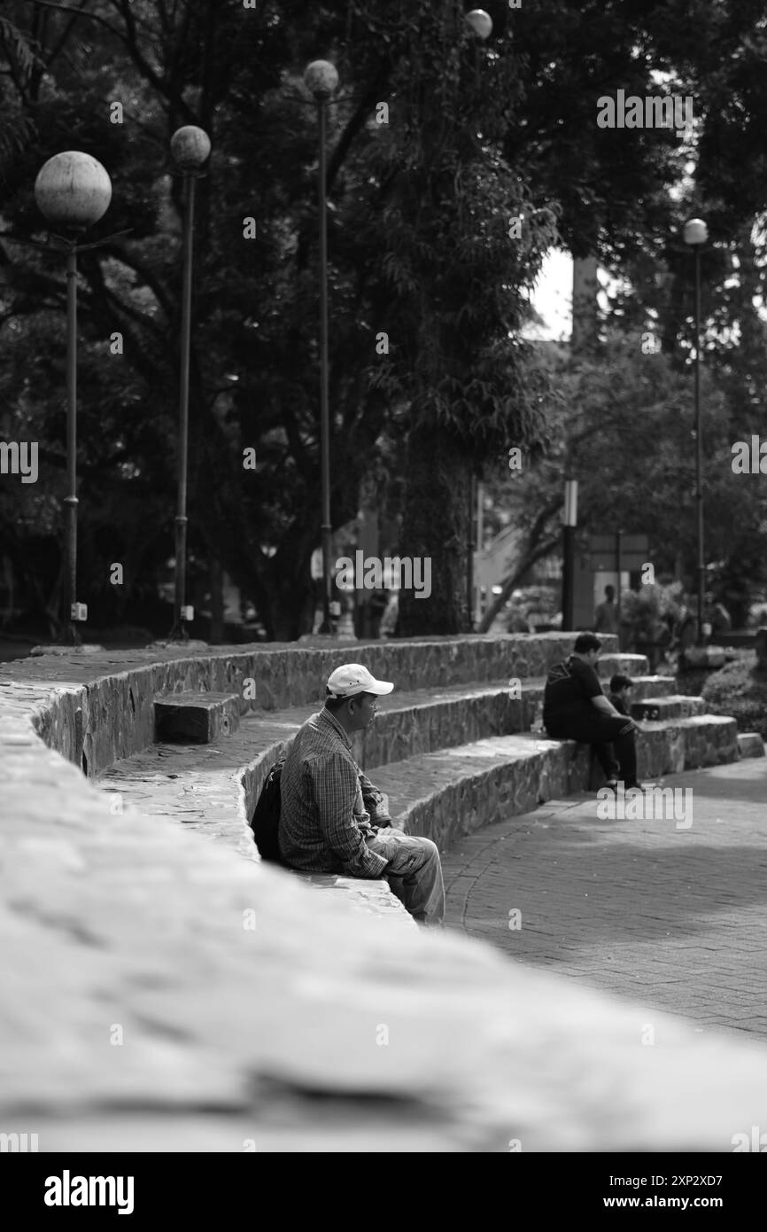 An old man sitting resting on a terraced bench in the middle of the ...