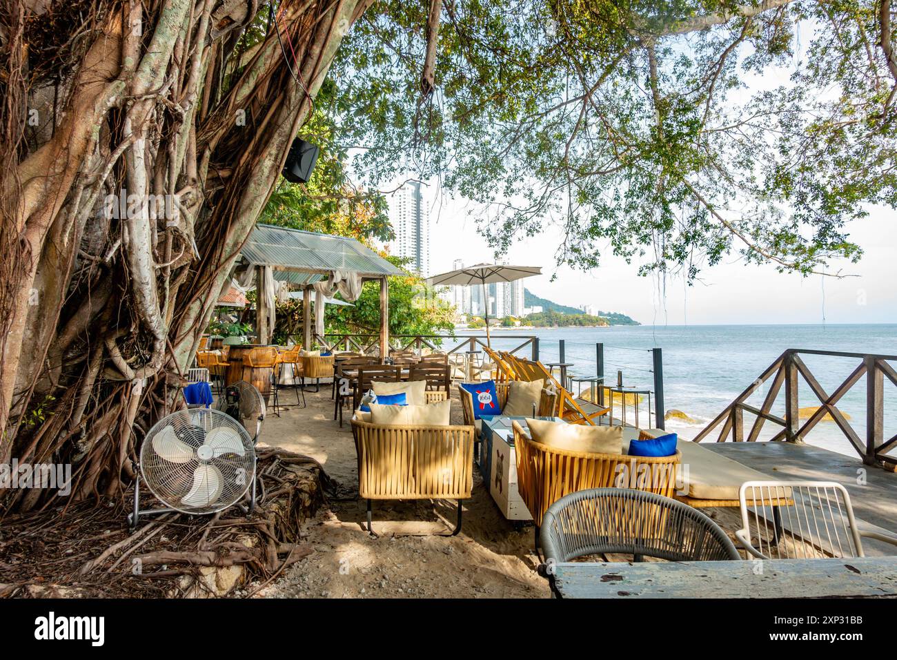 Tables and chairs at a restaurant with views over Tanjing Tokong beach ...