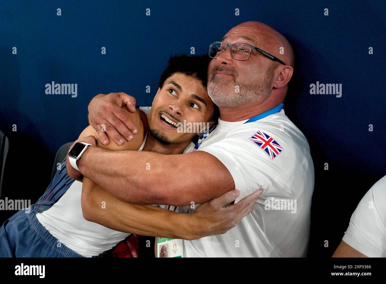 Jake Jarman, of Britain, gets a hug from coach Ben Howells, right ...