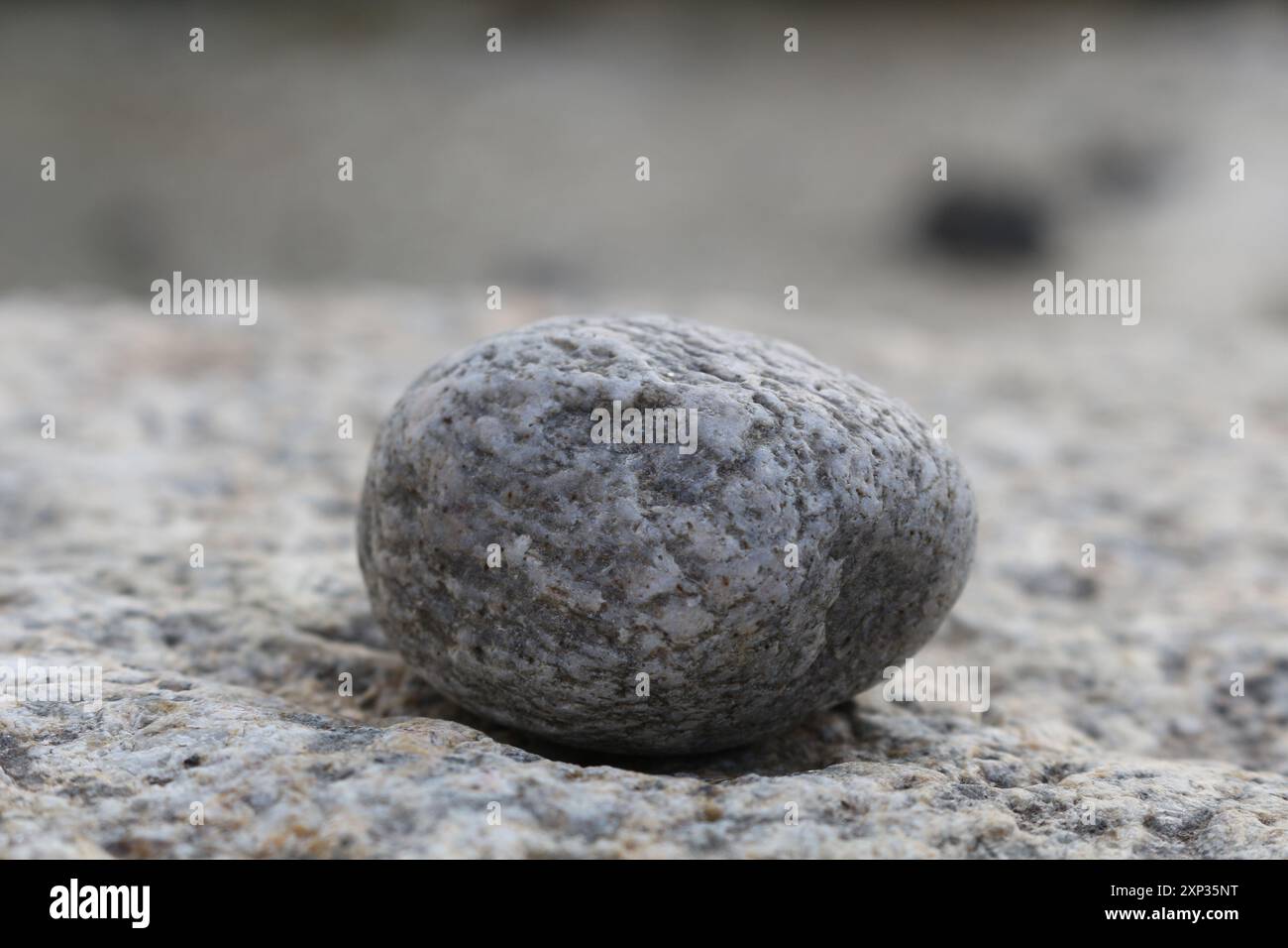 A small round rock lying on top of a large rock Stock Photo - Alamy