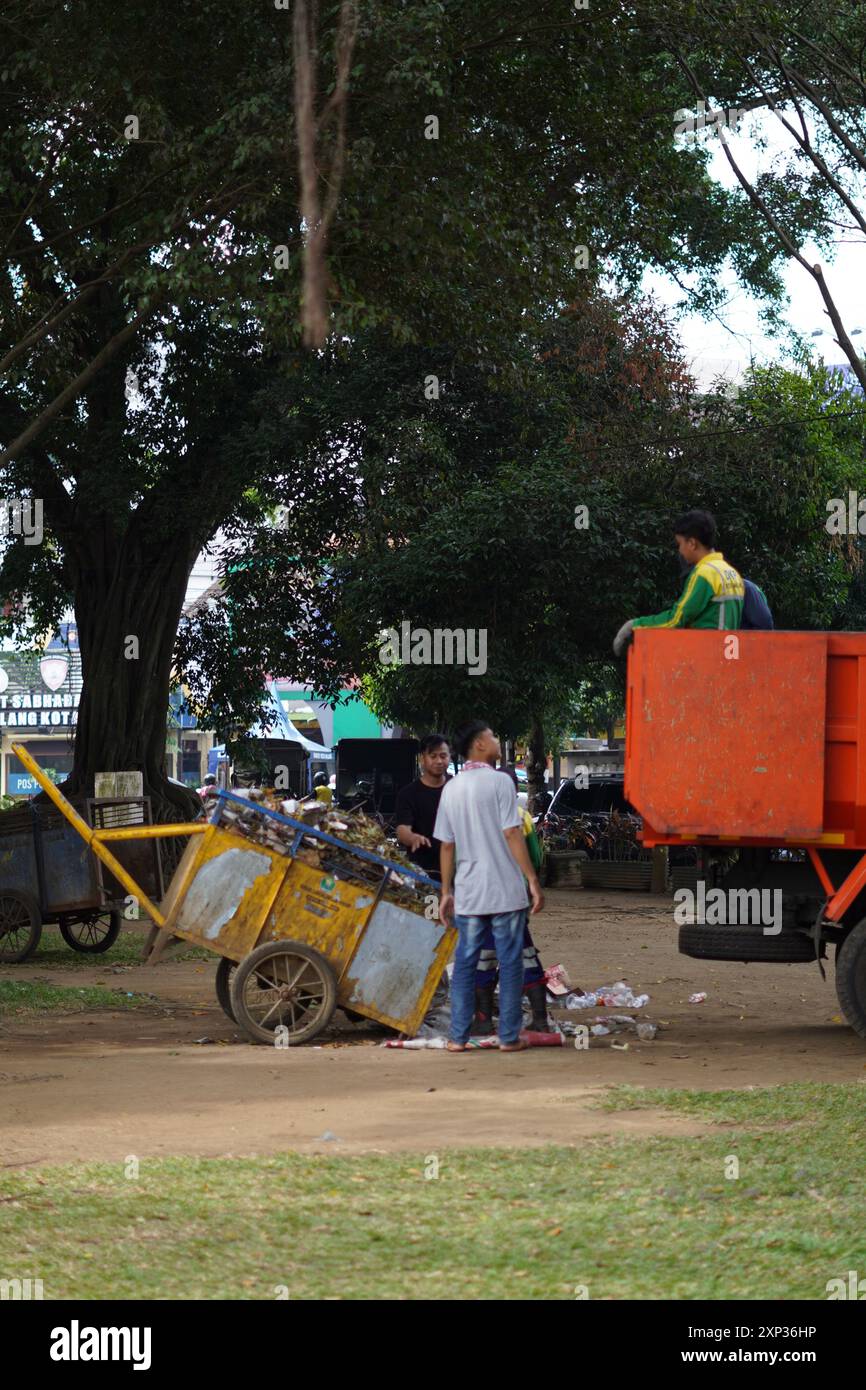 A group of people moving garbage from carts to garbage trucks in the ...