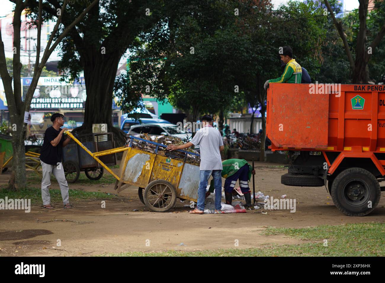 A group of people moving garbage from carts to garbage trucks in the ...