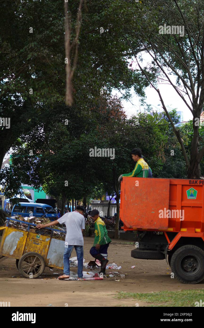 A group of people moving garbage from carts to garbage trucks in the ...