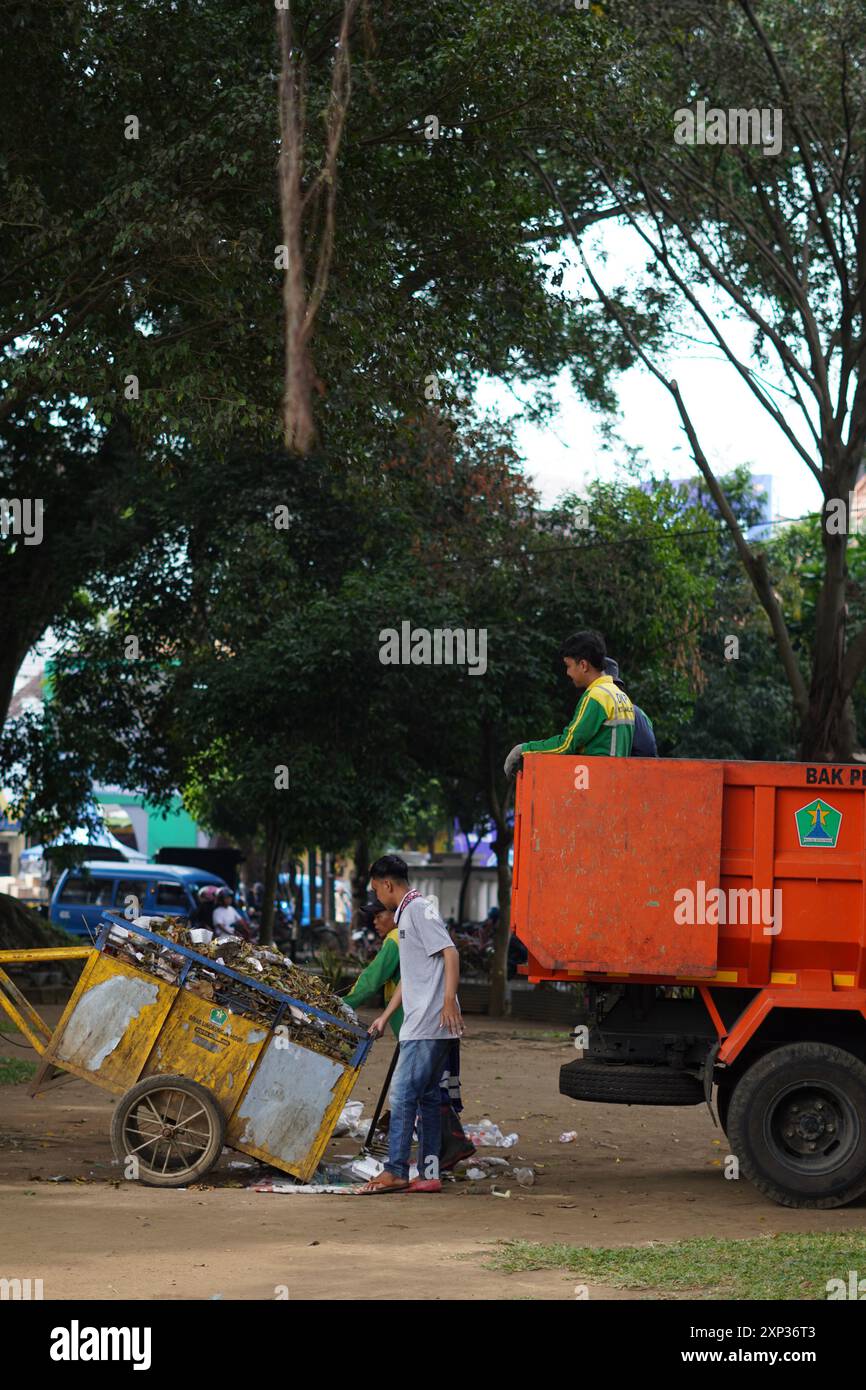A group of people moving garbage from carts to garbage trucks in the ...