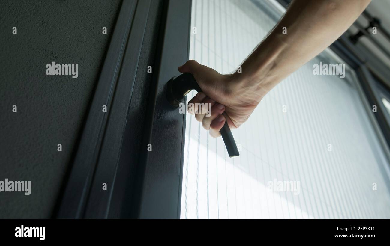 A close-up shot of a hand gripping and opening a modern window handle ...