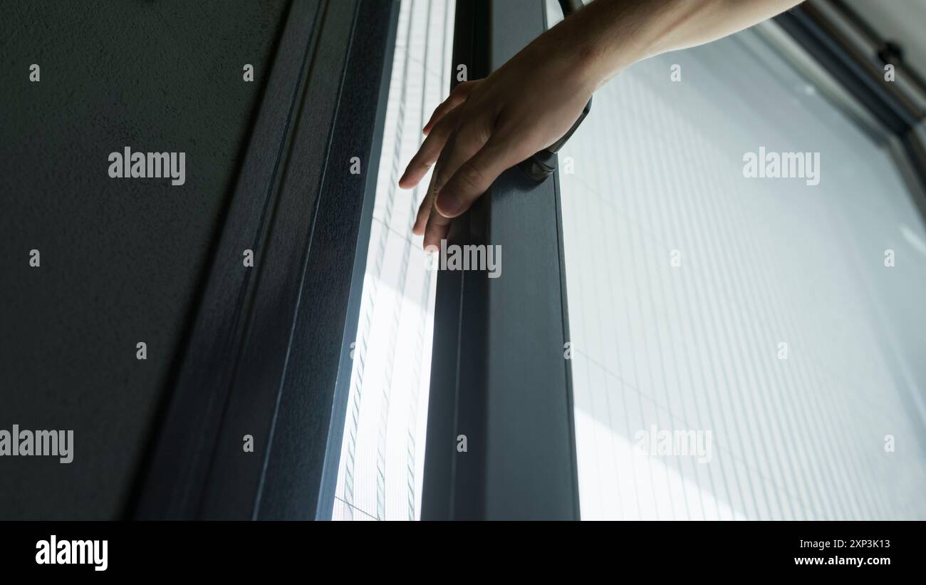 A close-up shot of a hand gripping and opening a sliding glass door ...