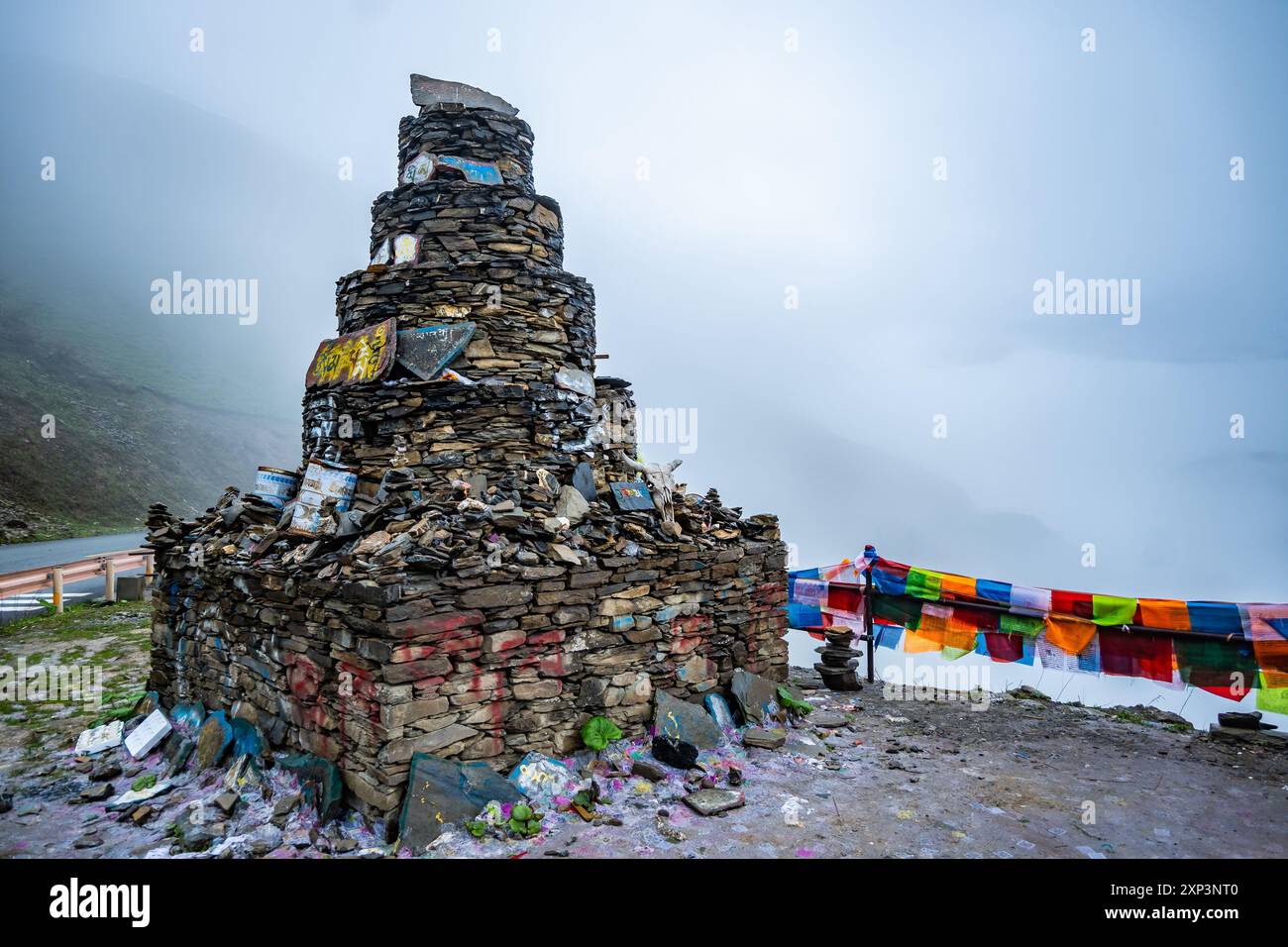 A traditional Tibetan stone prayer pile (Mani) and flags by side of ...